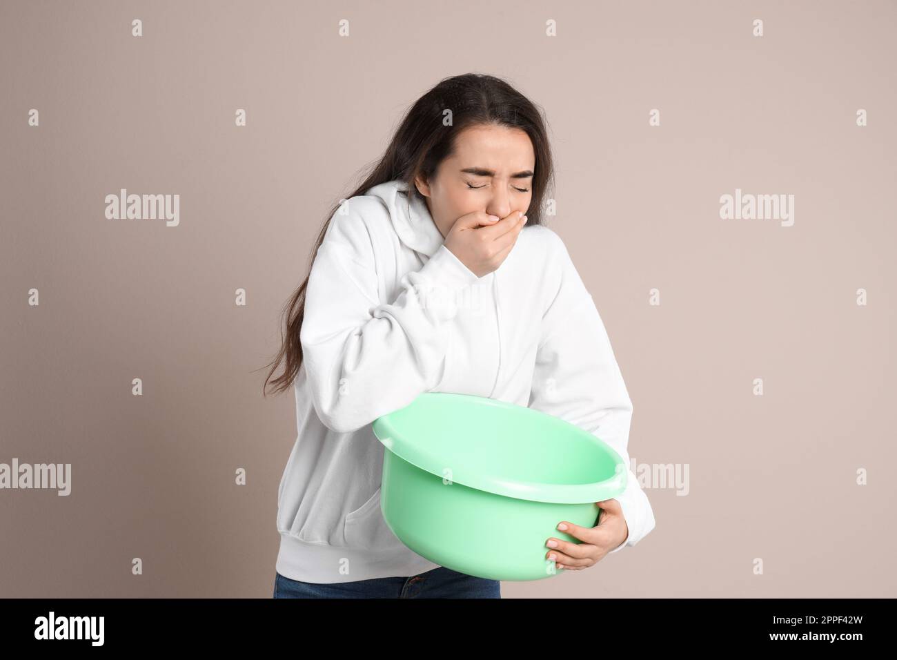Young woman with basin suffering from nausea on beige background. Food ...