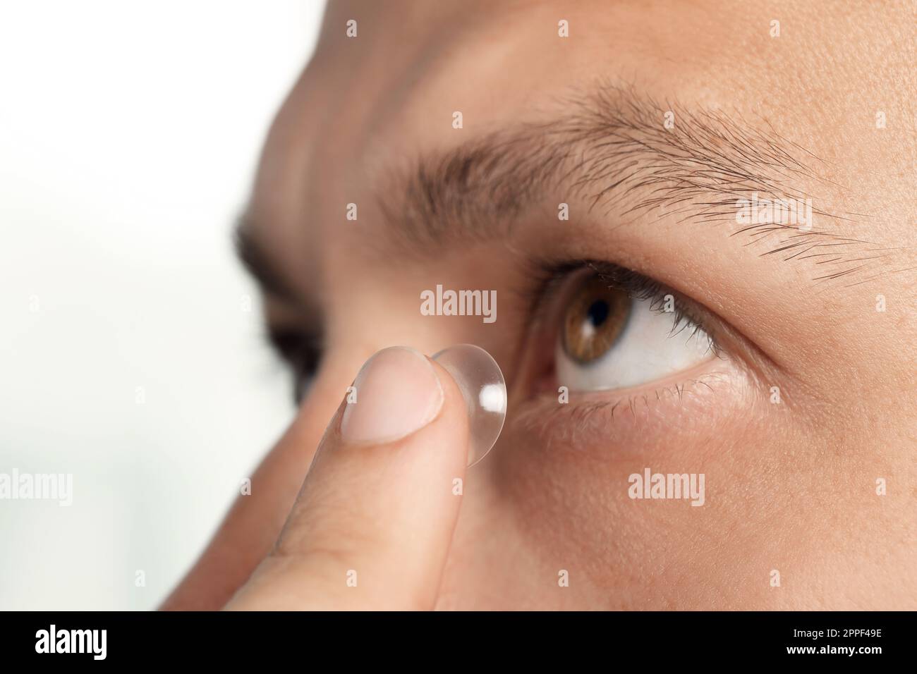 Man putting contact lens in his eye on white background, closeup Stock ...