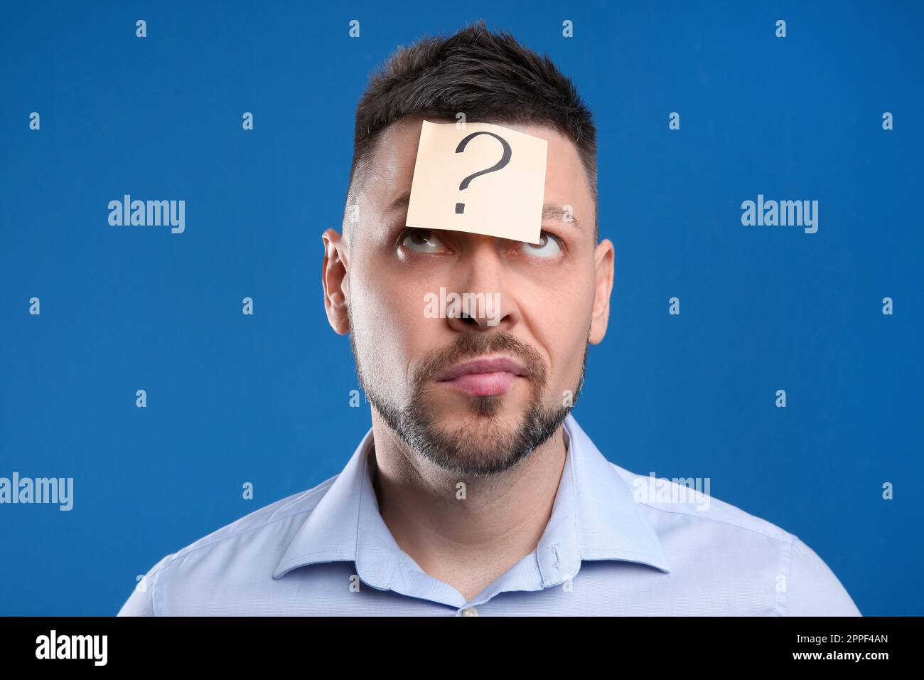 Emotional man with question mark on blue background Stock Photo - Alamy