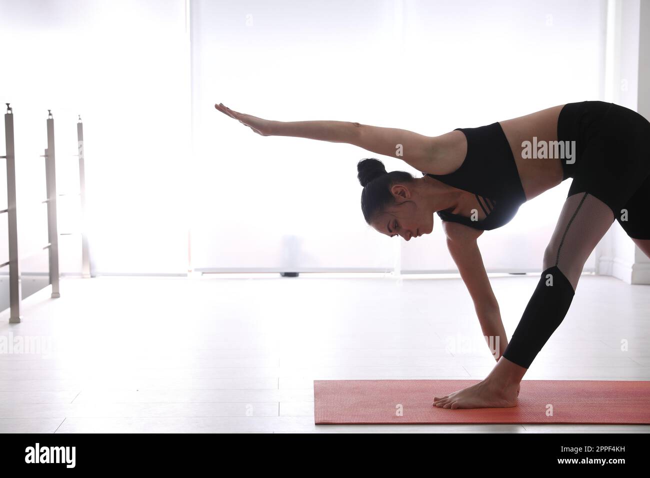 Young woman practicing extended triangle asana in yoga studio. Utthita ...