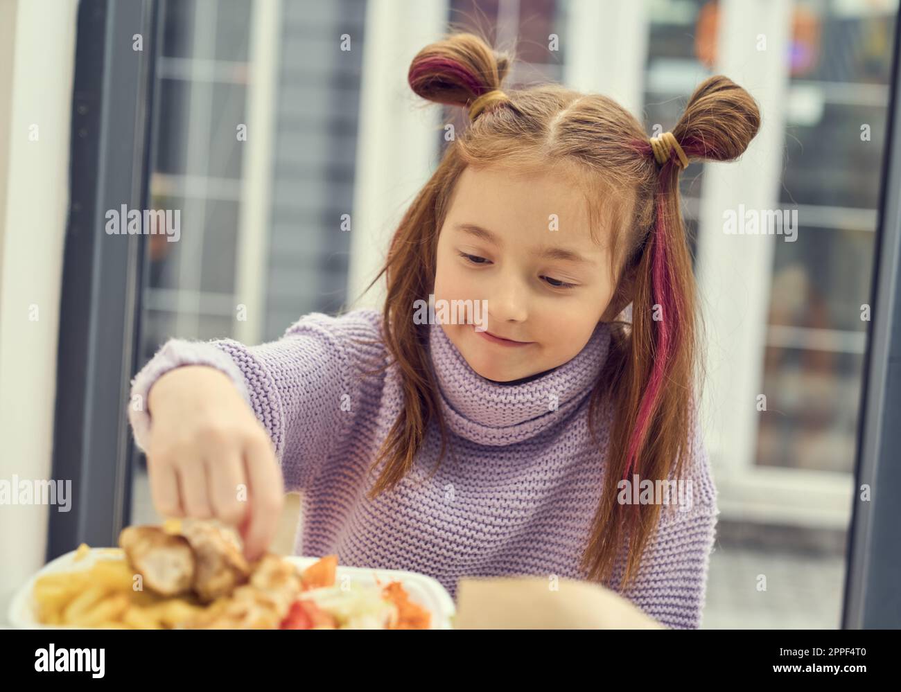 Cute little girl with ponytails eating fast food with hands. Hungry ...