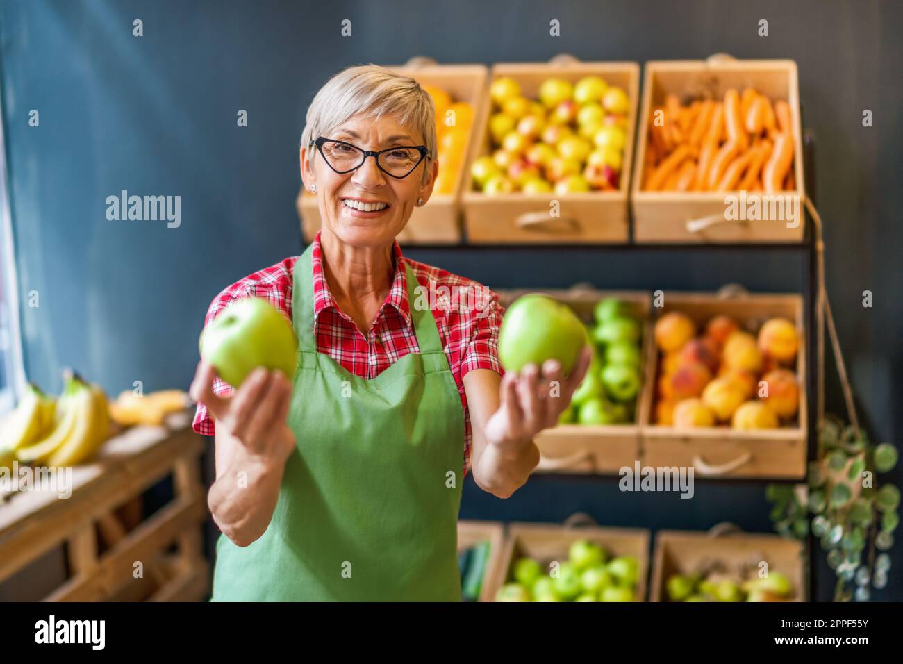 Worker in fruits and vegetables shop is holding apples Stock Photo - Alamy