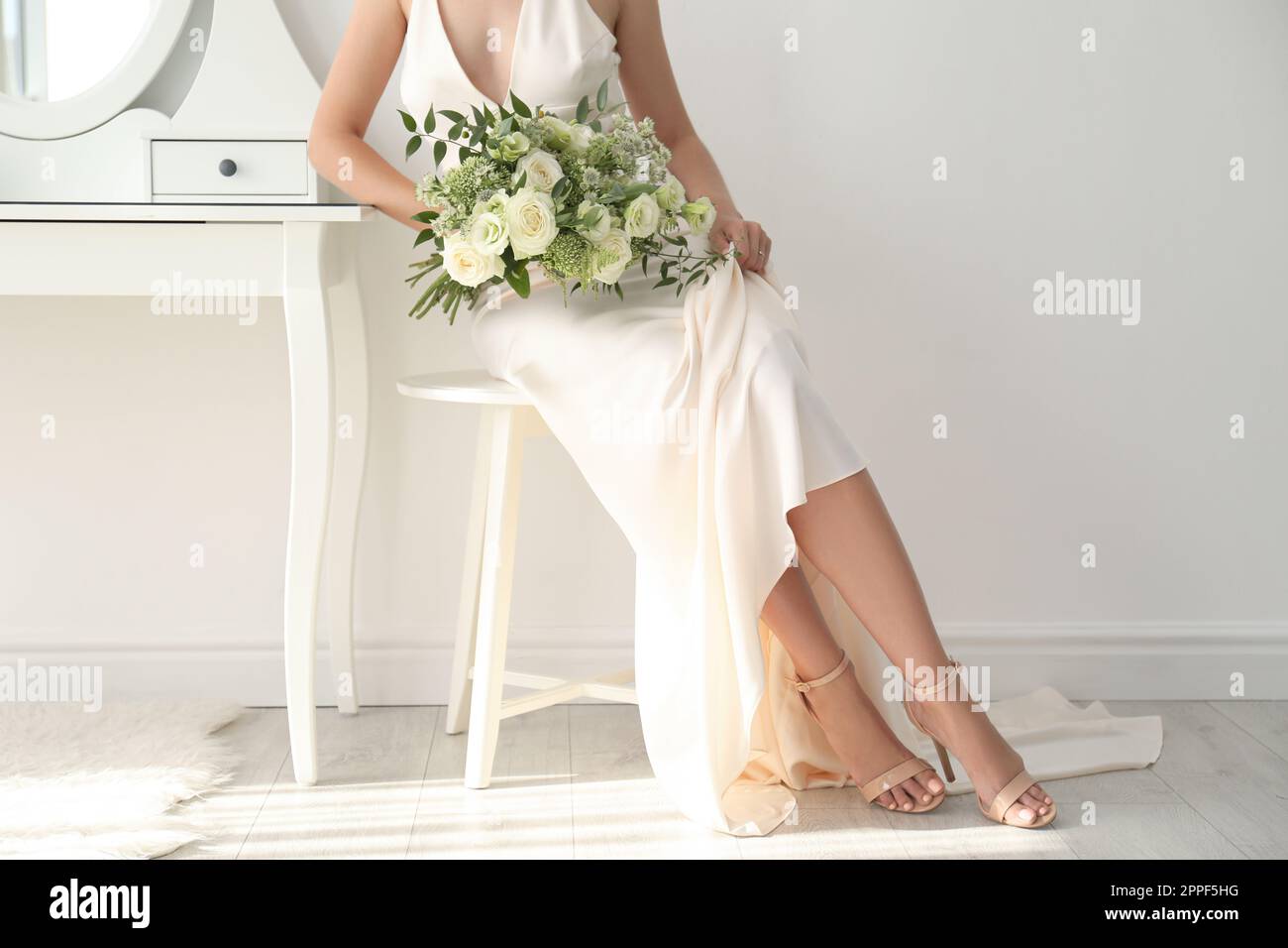Young bride wearing wedding dress with beautiful bouquet in room ...