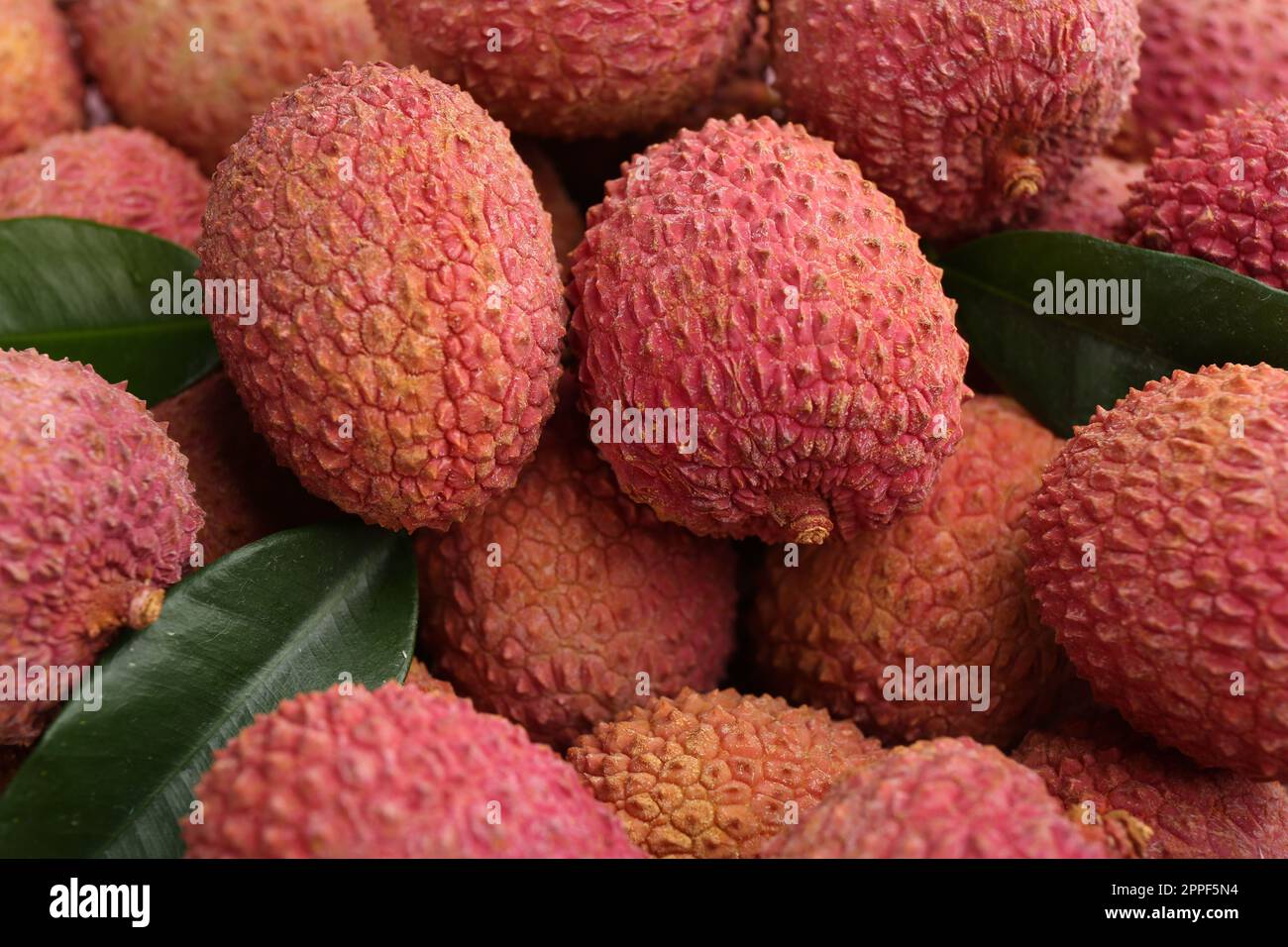 Pile of fresh ripe lychees with leaves as background, closeup Stock ...