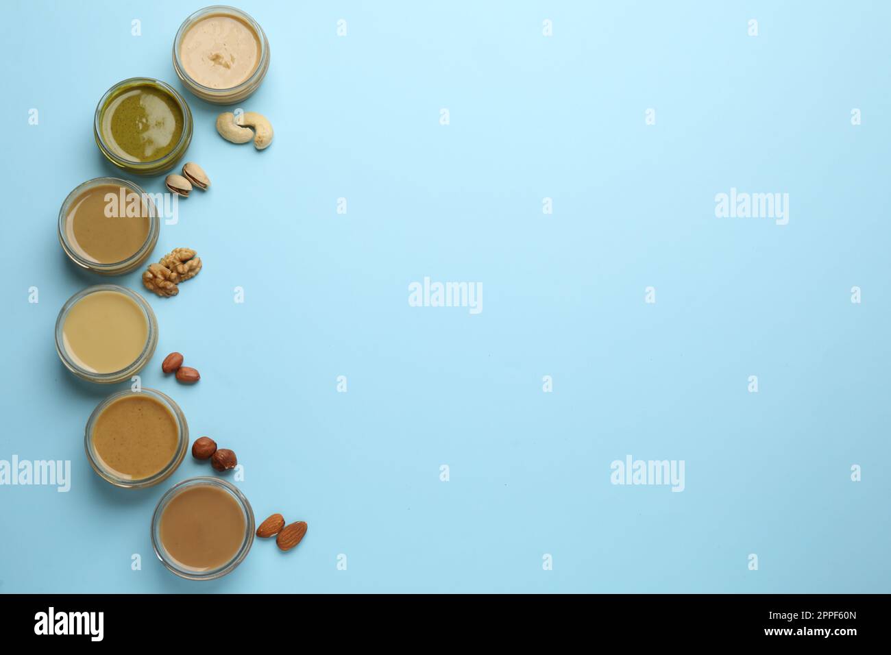 Different Types Of Delicious Nut Butters And Ingredients On Light Blue Background Flat Lay