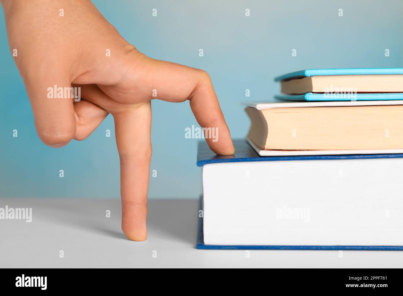 Woman imitating stepping up on books with her fingers against light ...