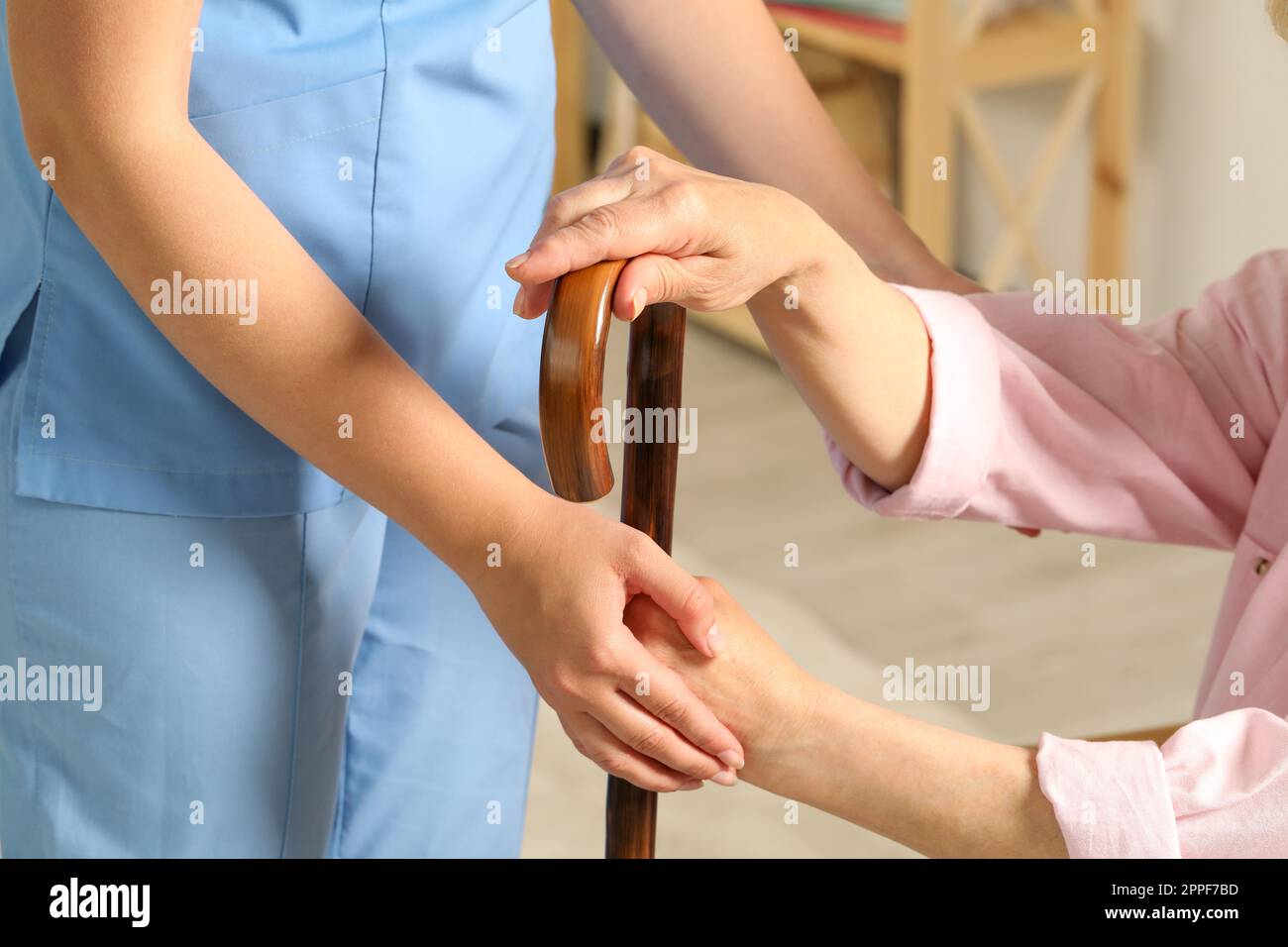 Elderly woman with walking cane and female caregiver indoors, closeup ...