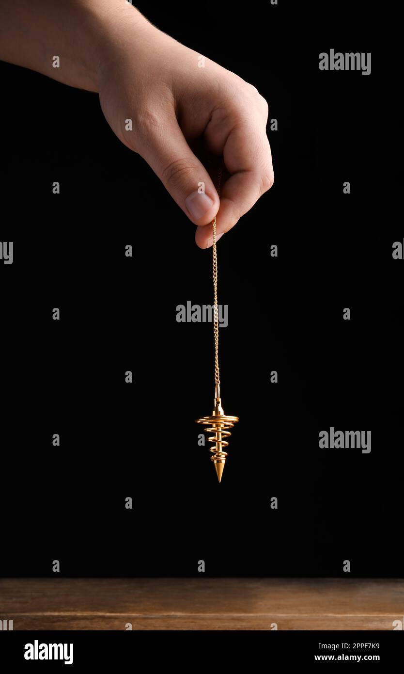 Psychotherapist with pendulum on black background, closeup ...