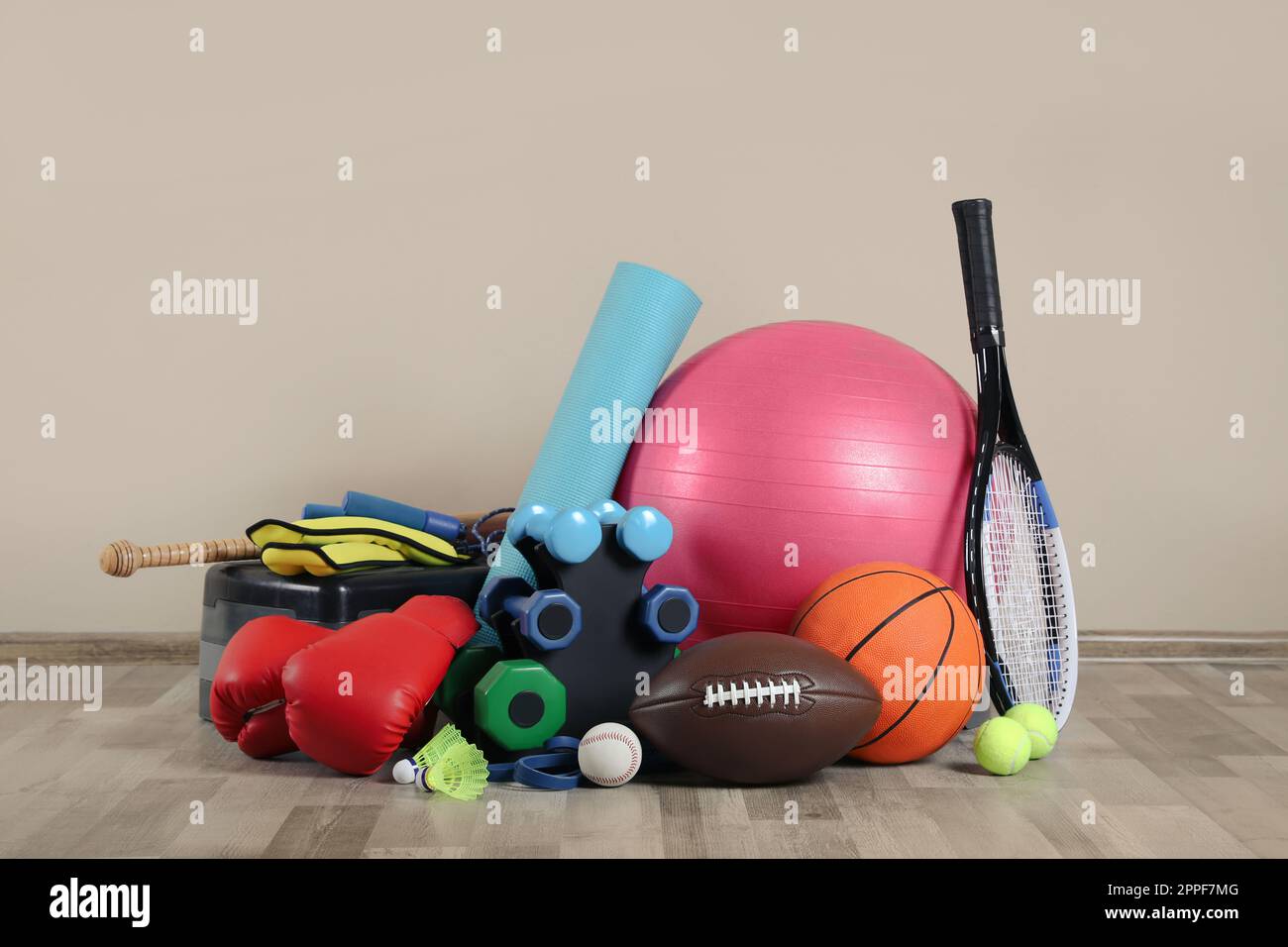 Set of different sports equipment on floor near beige wall Stock Photo ...