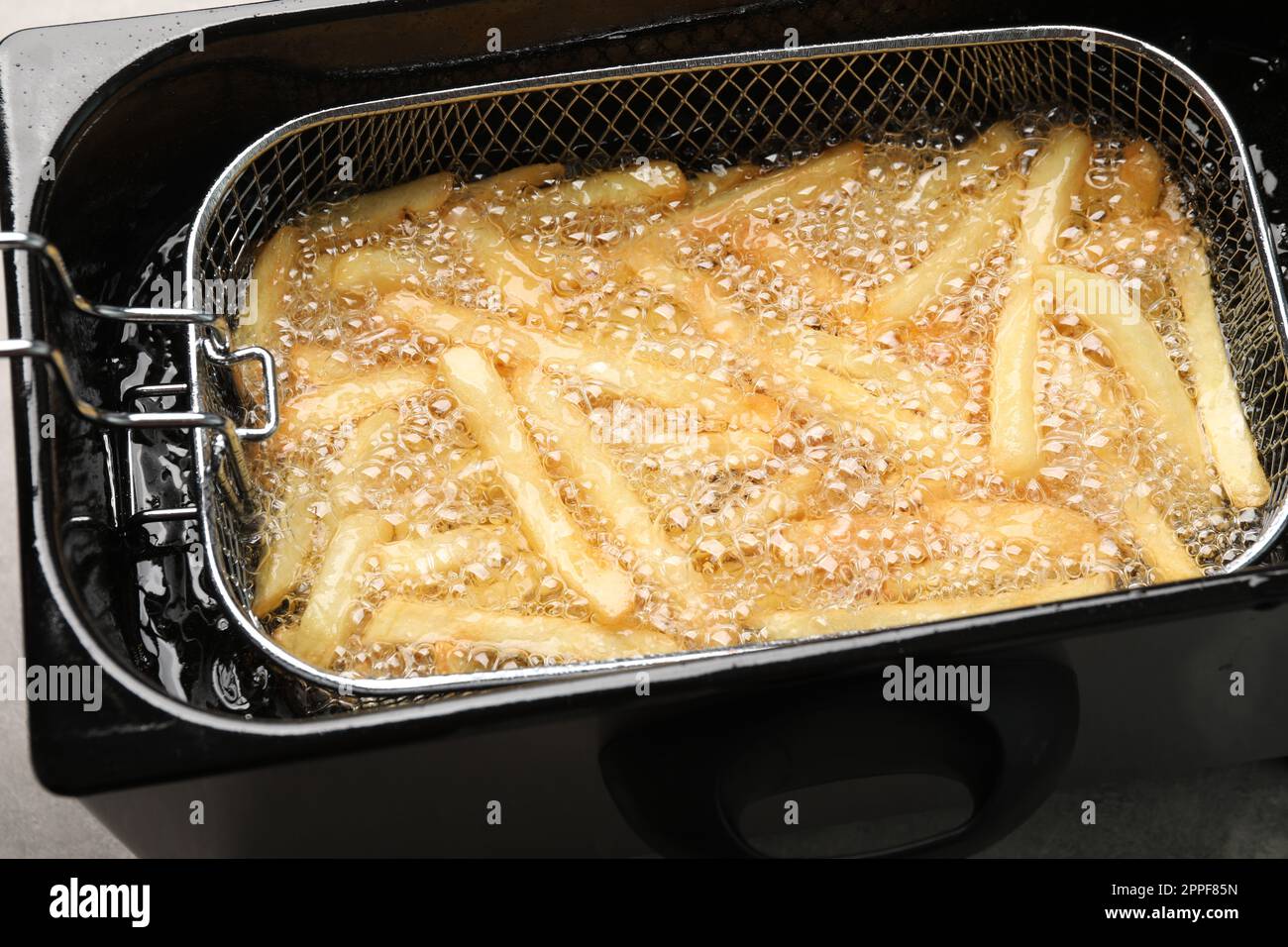 Cooking delicious french fries in hot oil, closeup Stock Photo - Alamy
