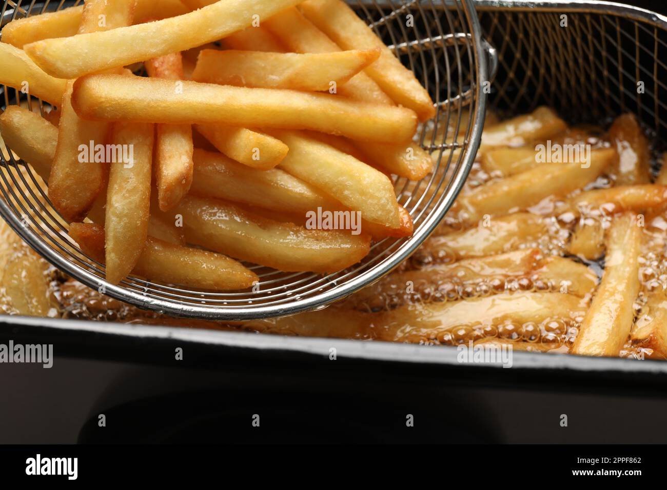 Delicious freshly prepared french fries in metal strainer, closeup ...