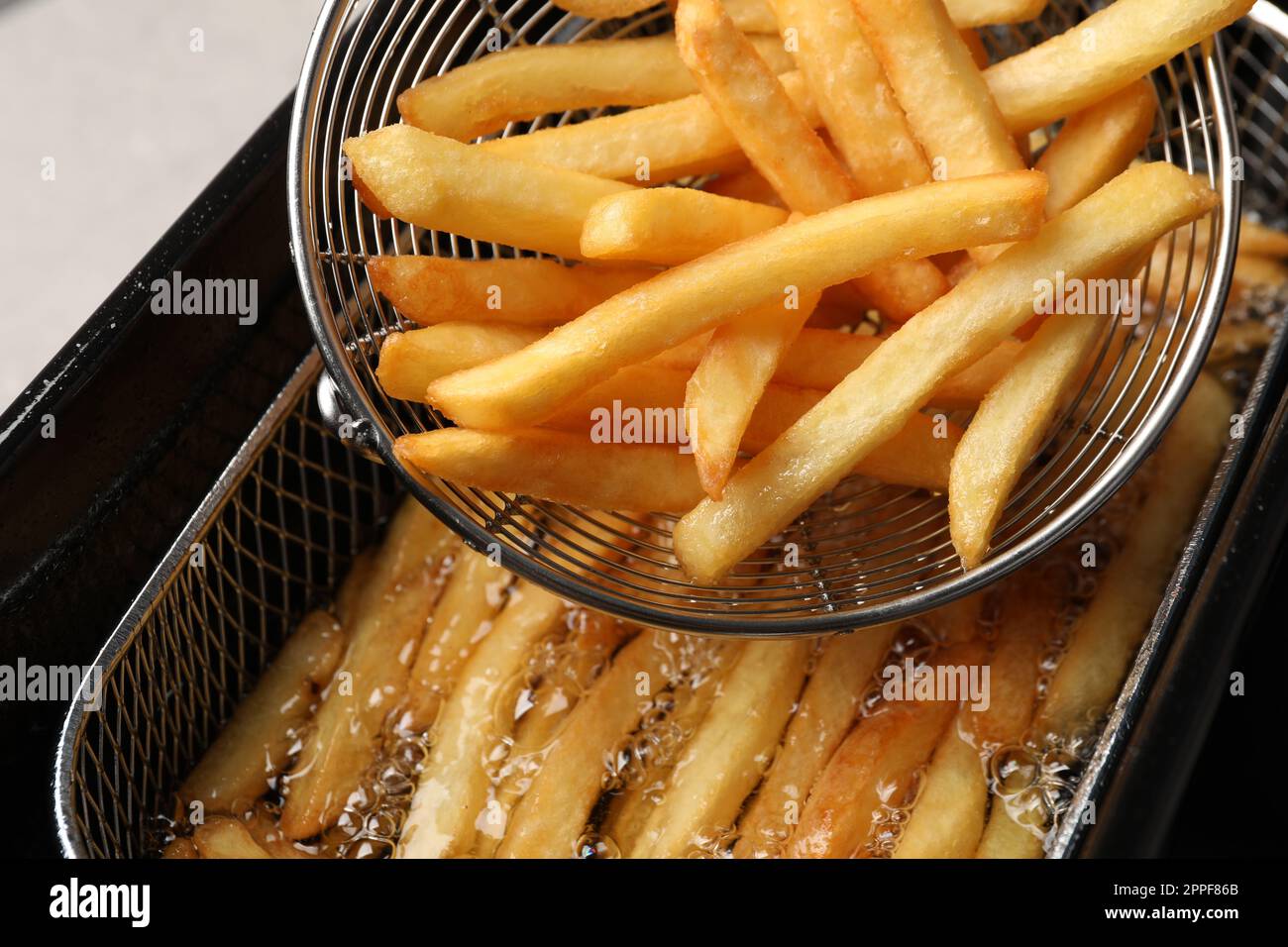 Delicious freshly prepared french fries in metal strainer, closeup ...