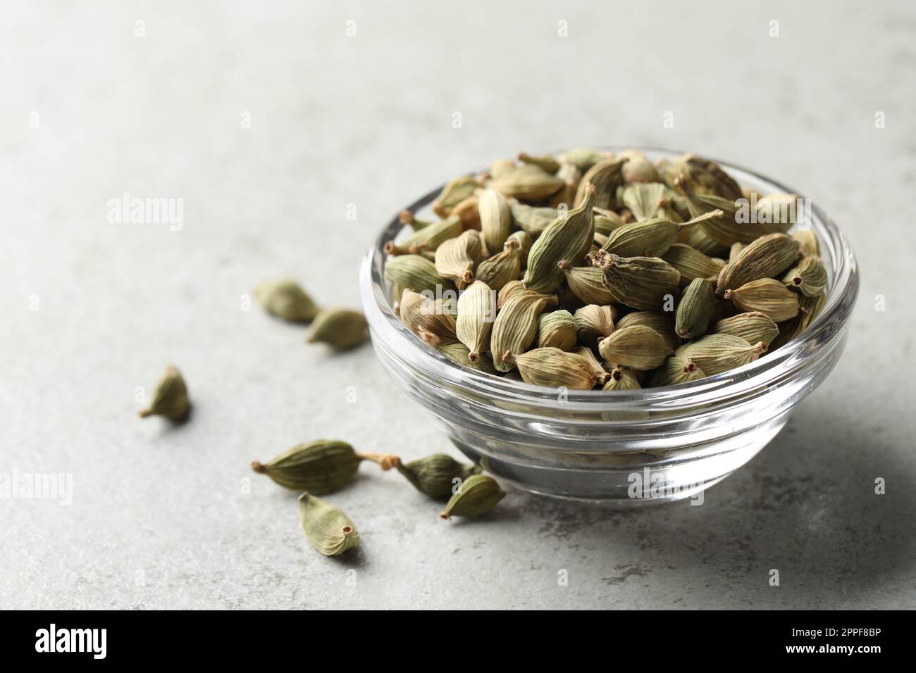 Glass bowl of dry cardamom pods on light grey table Stock Photo - Alamy