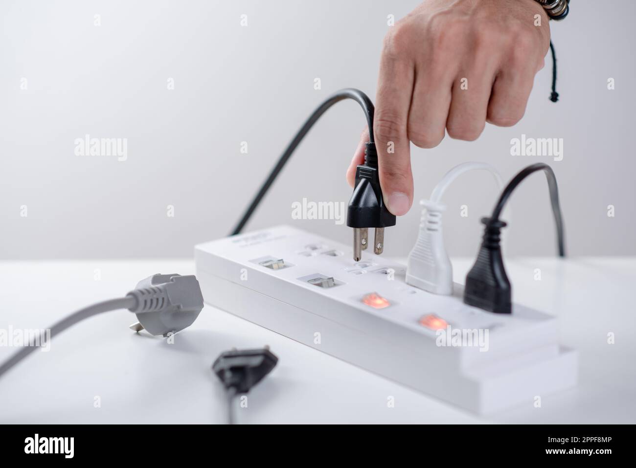 Closeup of a mans hand inserting a plug into electrical power strip ...