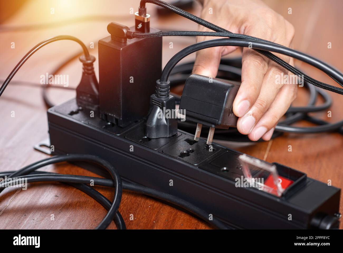 Closeup of a mans hand inserting a plug into electrical power strip ...