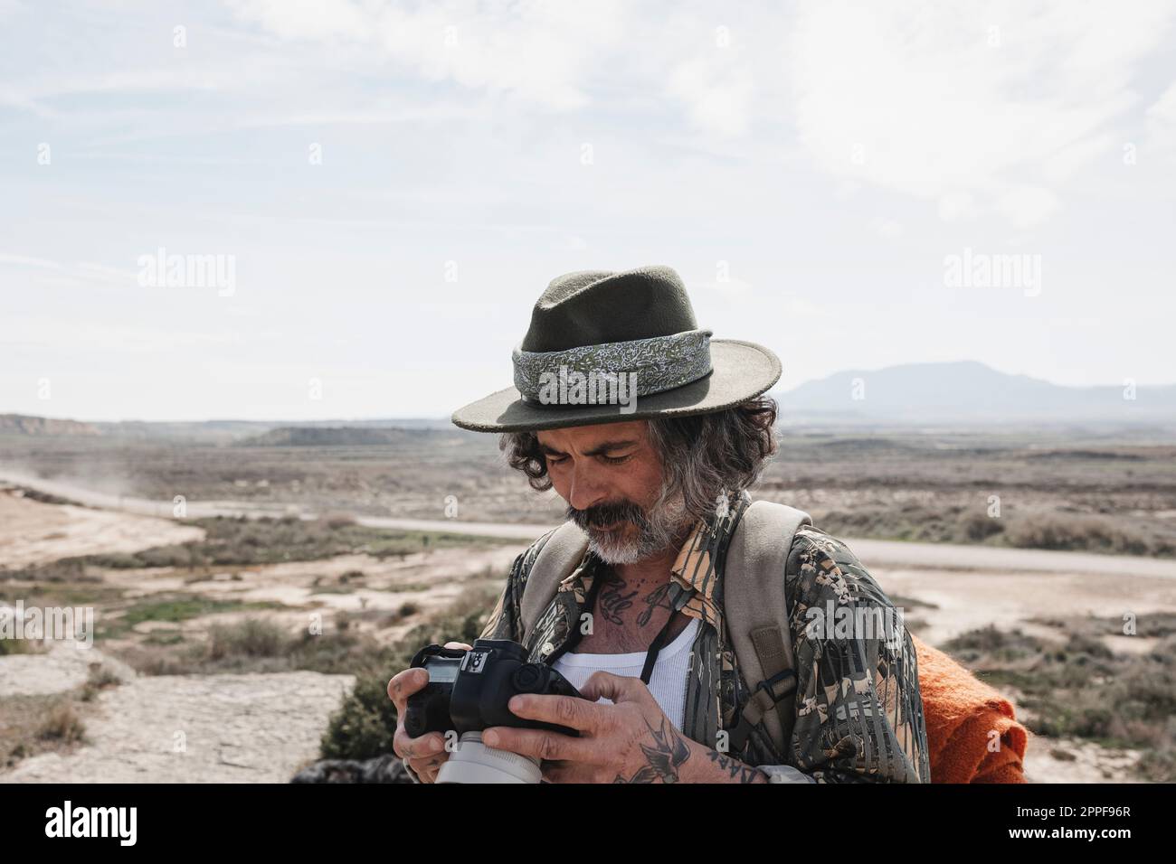 Traveler man with hat looking at the photos he takes from his camera in ...
