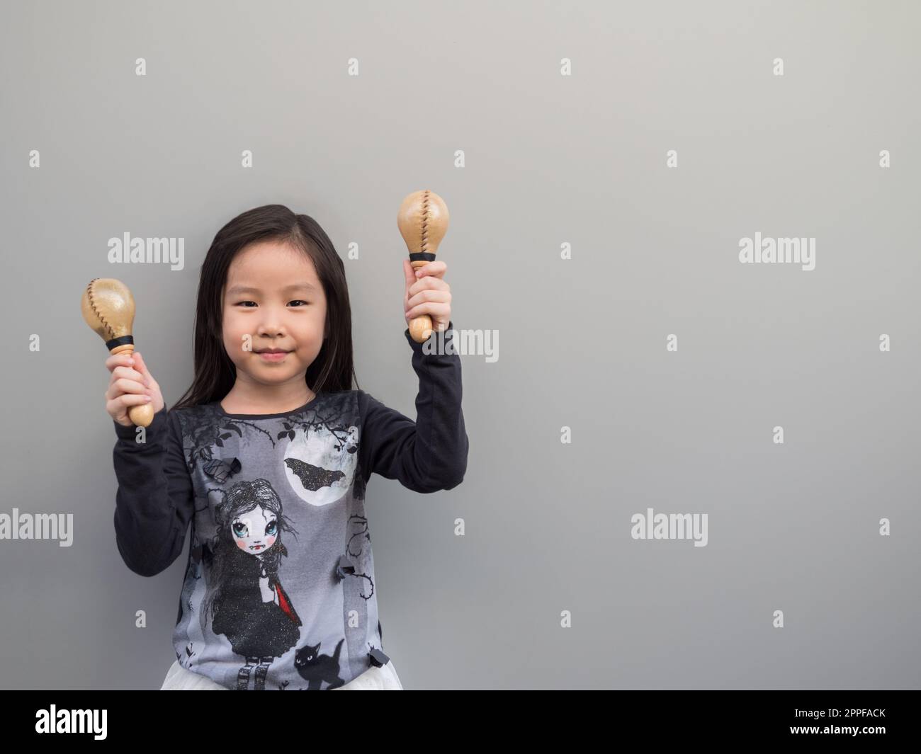 Little asian child play the maracas, gray background Stock Photo - Alamy