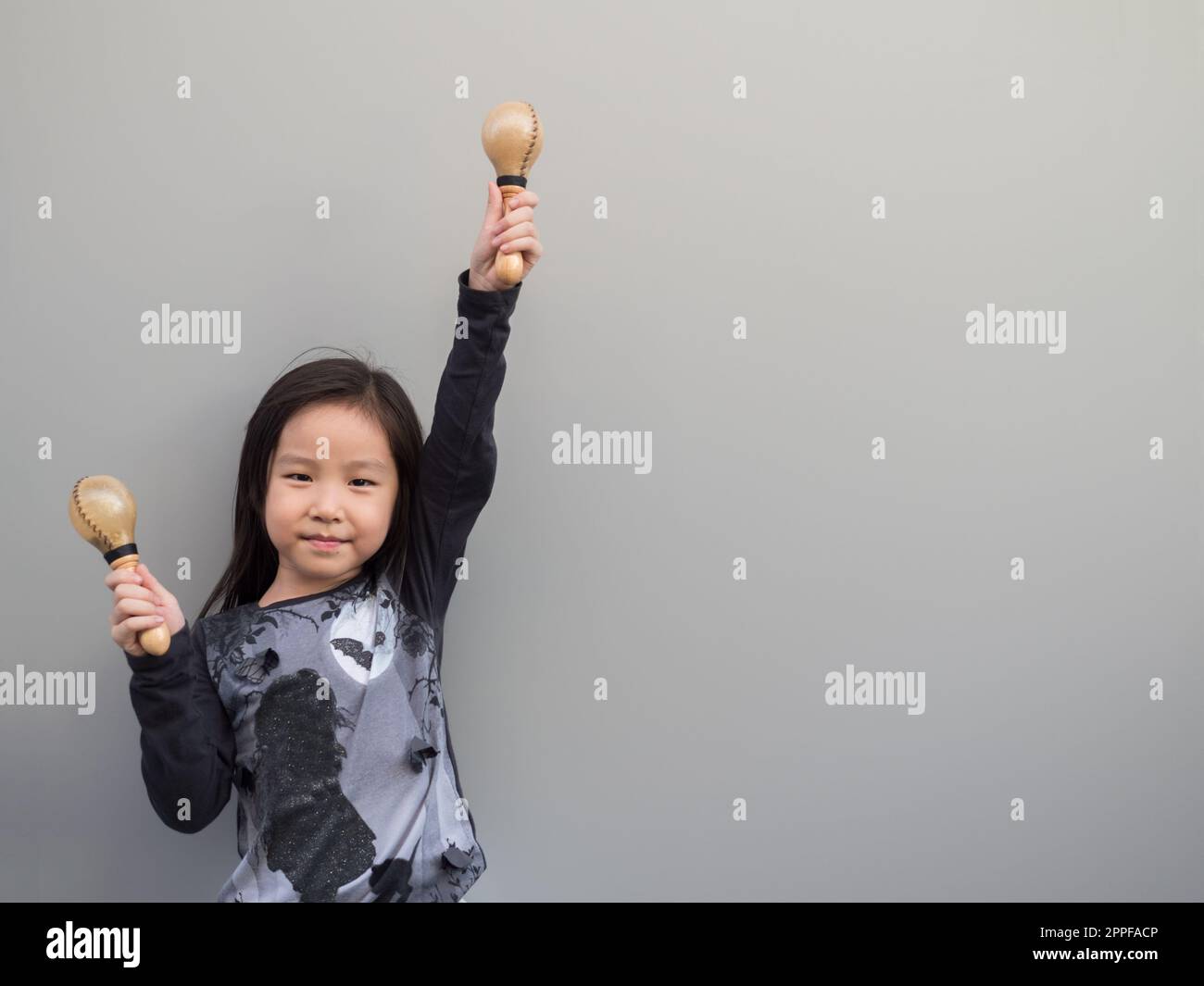 Little asian child play the maracas, gray background Stock Photo - Alamy