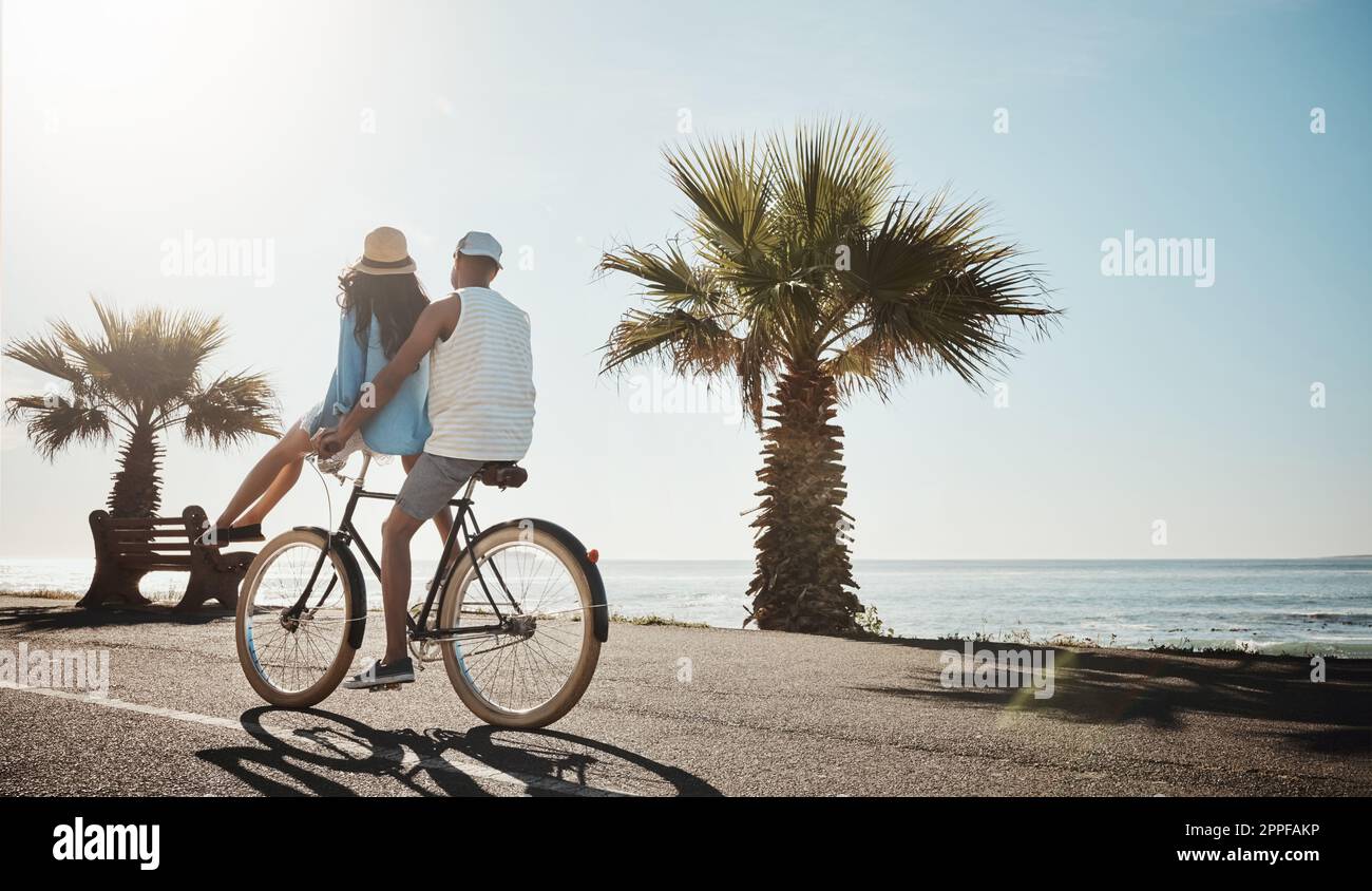 They enjoy long cycles along the beach. a young couple riding a bicycle ...