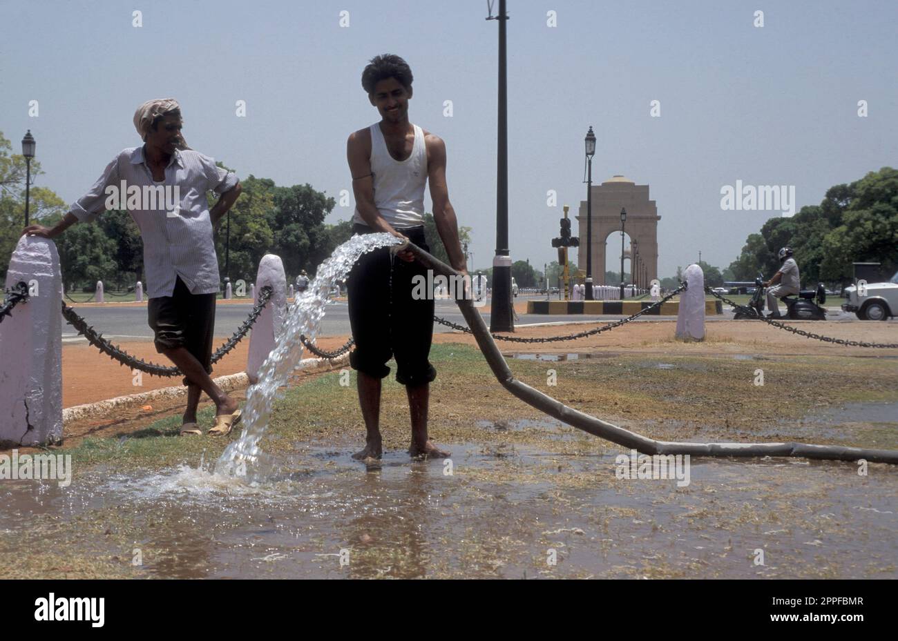 a men splashes water on park in front of the Delhi Gate in the city of ...