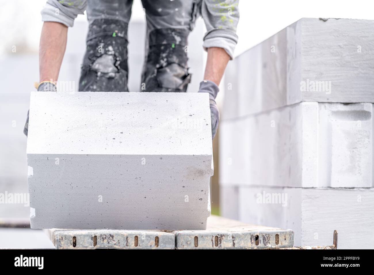 a mason builds the wall of a house from concrete bricks Stock Photo - Alamy