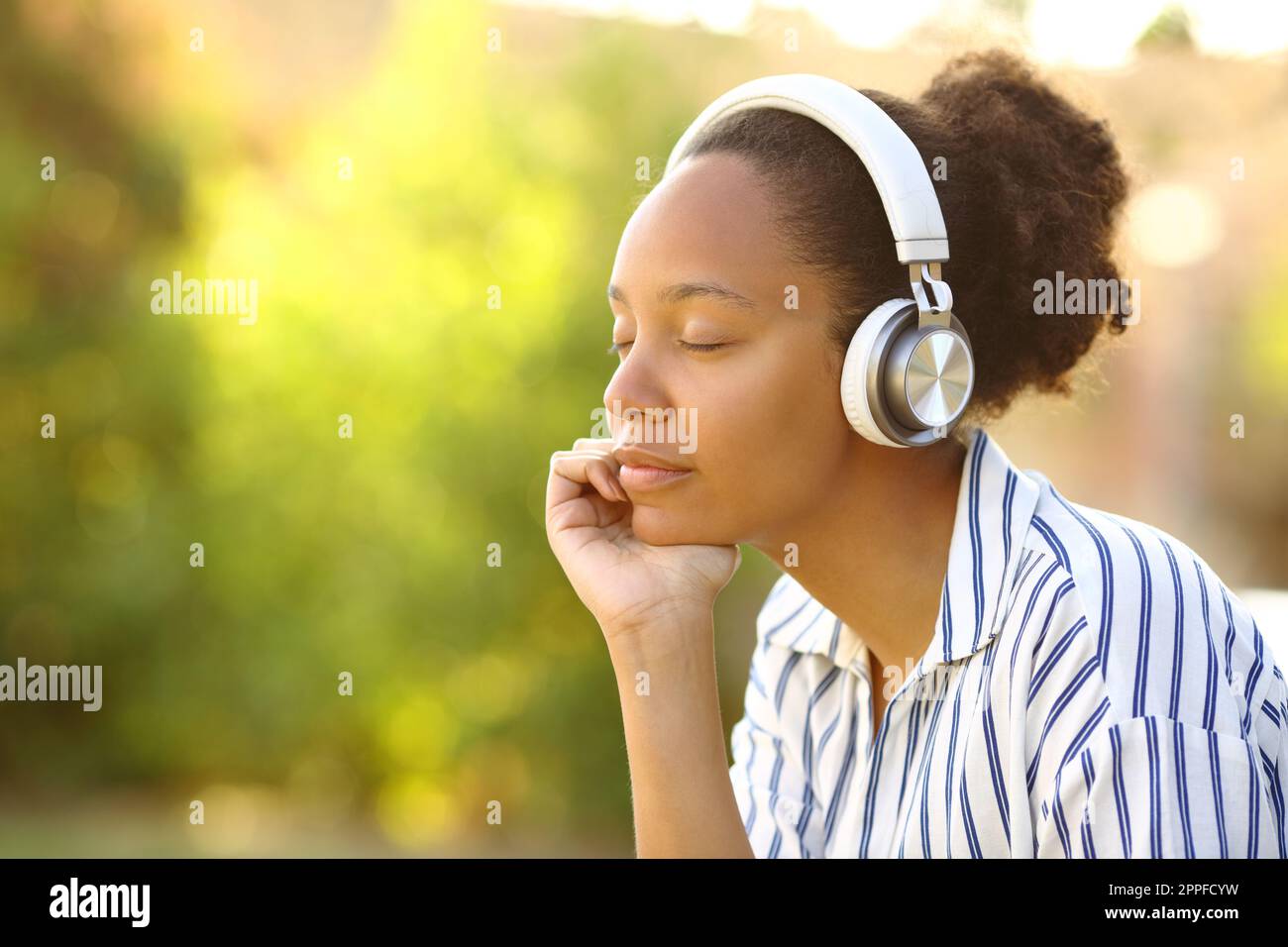 Relaxed Black Woman Wearing Headphone Listening Music Resting In A Park