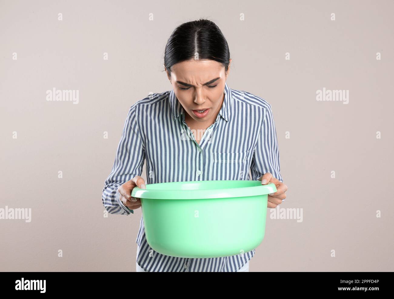 Woman with basin suffering from nausea on beige background. Food ...