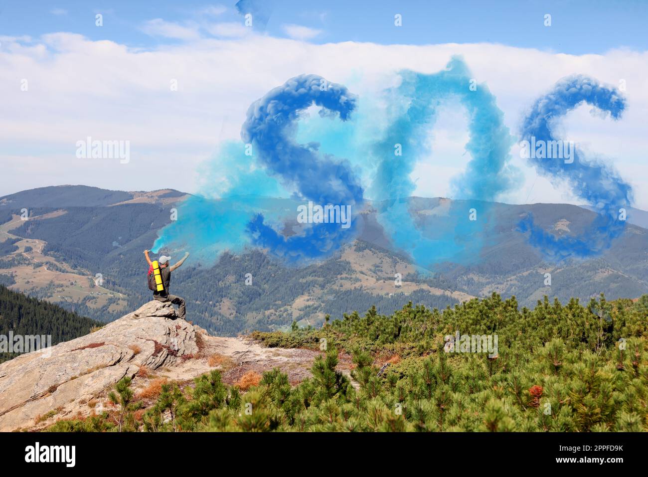 Man with backpack and word SOS made of color smoke bomb on rocky peak in mountains, back view ...