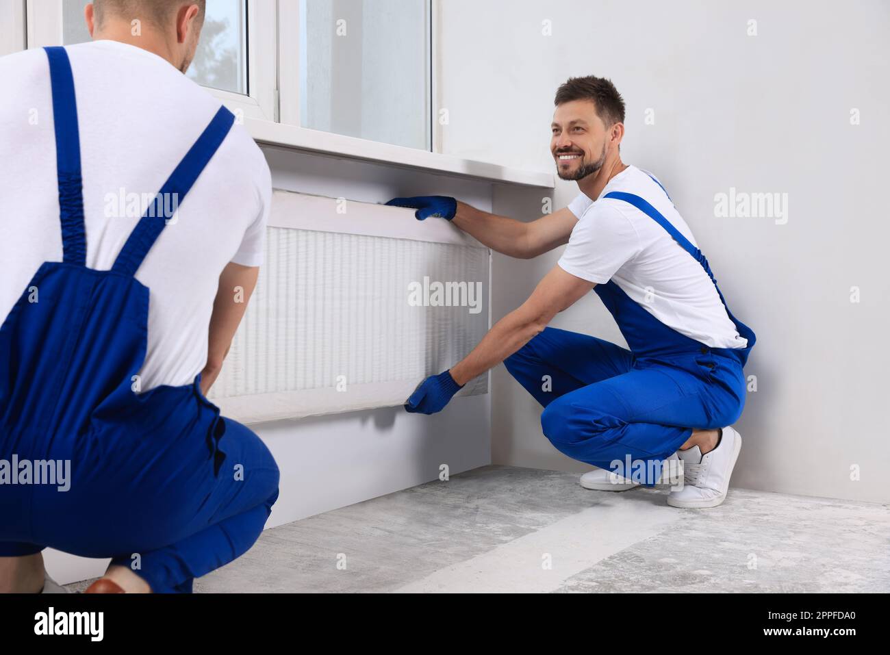 Professional plumbers installing new heating radiator in room Stock ...