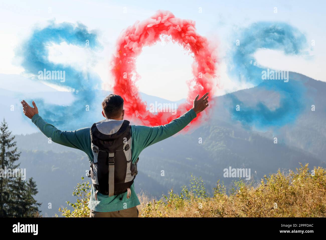 Man with backpack and word SOS made of color smoke bomb in mountains ...