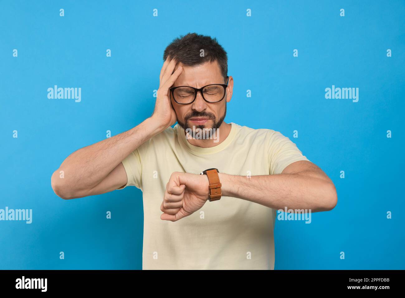 Man checking time on light blue background. Being late concept Stock ...