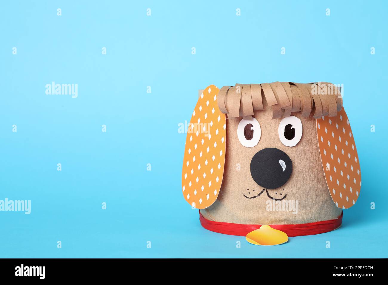 Toy dog made of toilet paper roll on light blue background. Space for ...