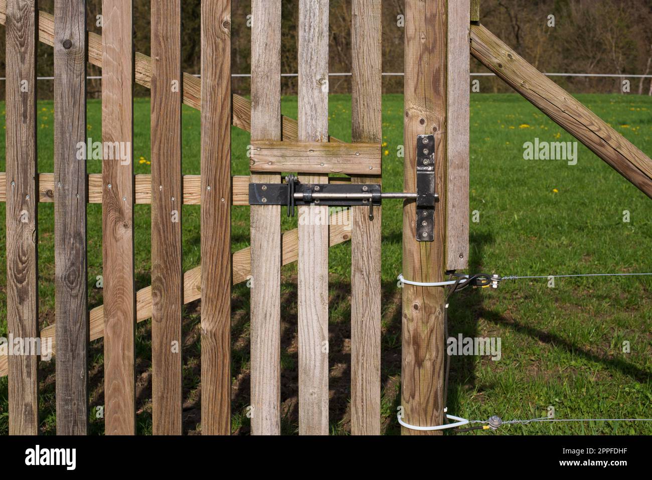 detail of a closed wooden gate at a pasture with a simple metal lock ...