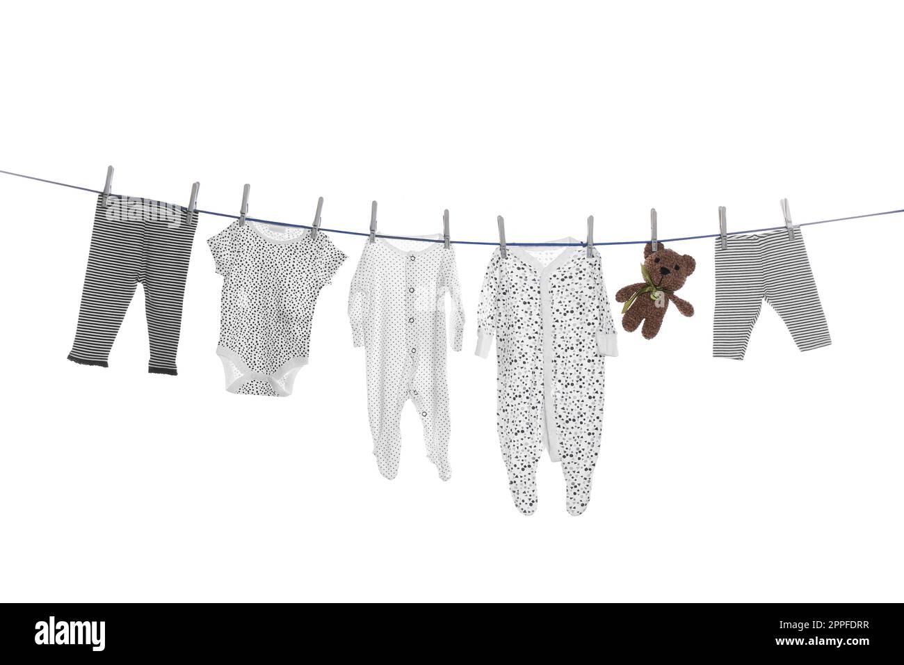 Different baby clothes and toy drying on laundry line against white ...