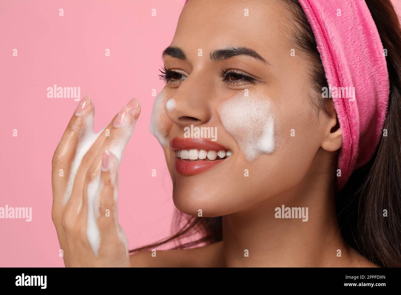 Beautiful woman applying facial cleansing foam on pink background, closeup Stock Photo - Alamy