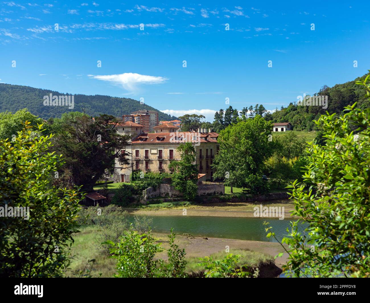 An old manor house on the river bank against background of high-rise ...