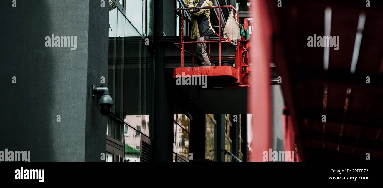 Female window cleaner cleaning glass windows on modern building high in ...