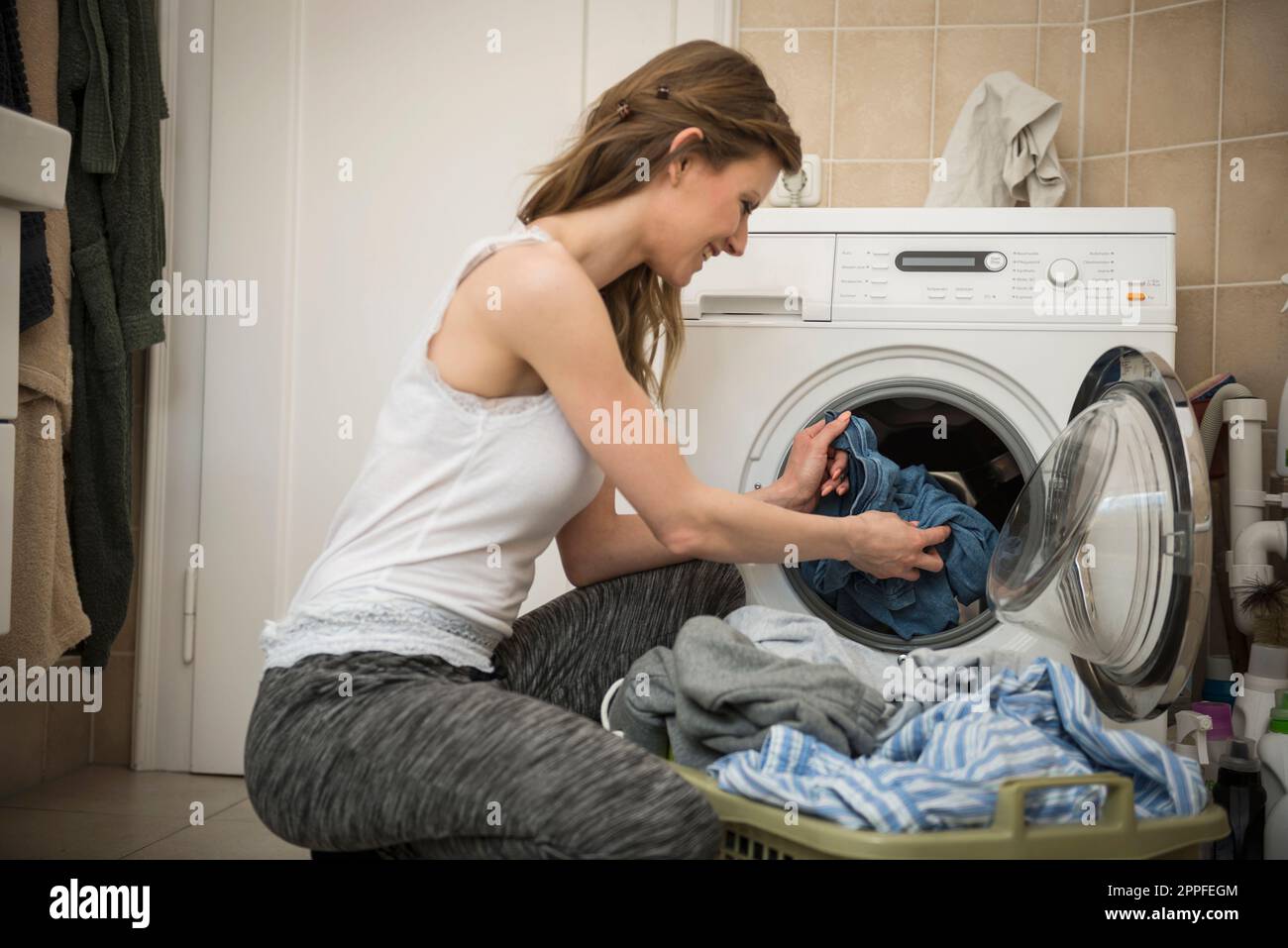 Young woman taking laundry out of washing machine, Munich, Bavaria ...