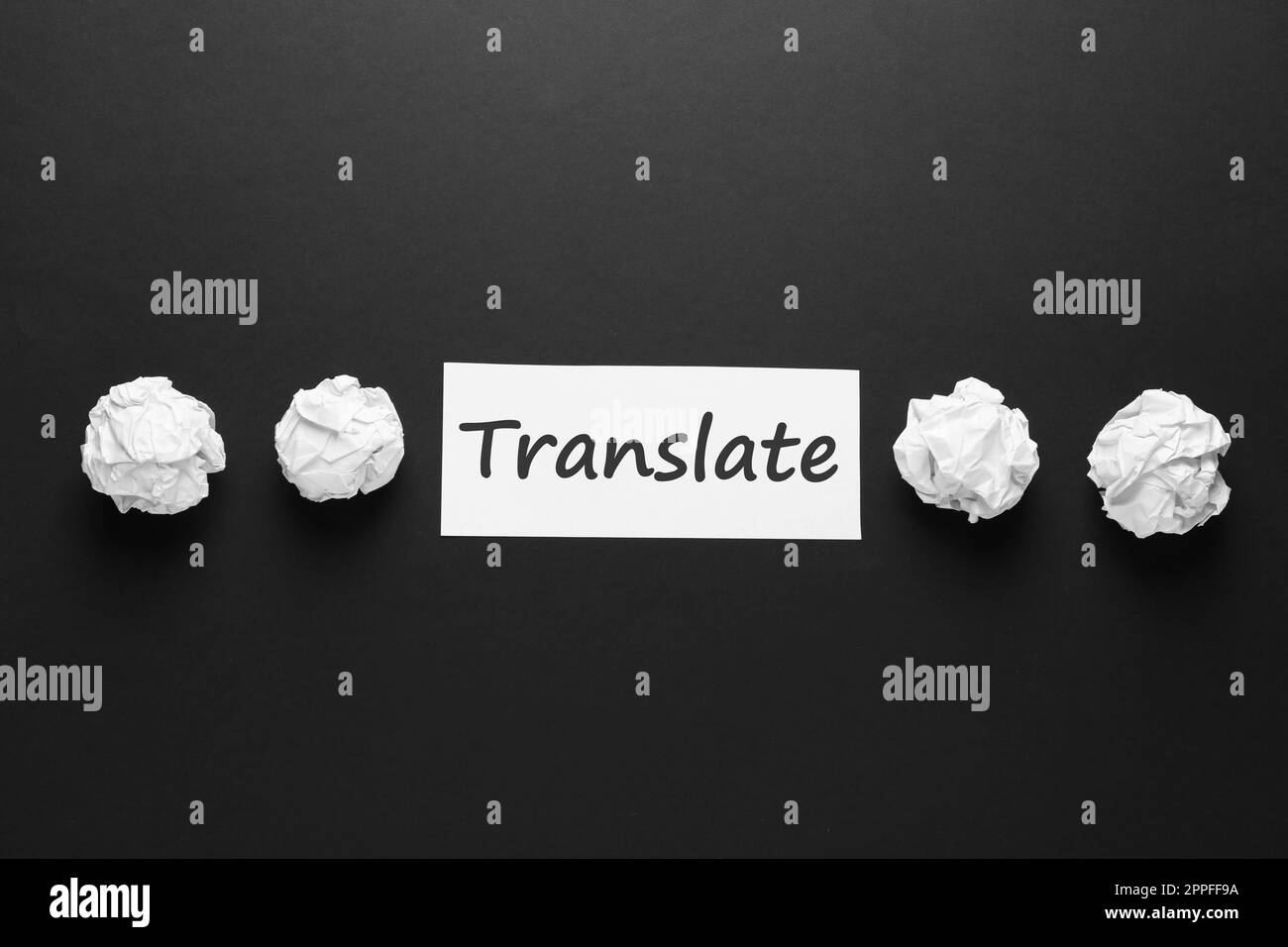 Card with word Translate and crumpled paper balls on black background ...