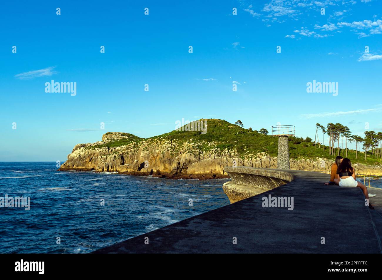 the girls are sitting on the embankment of the precipitous coast of the ...
