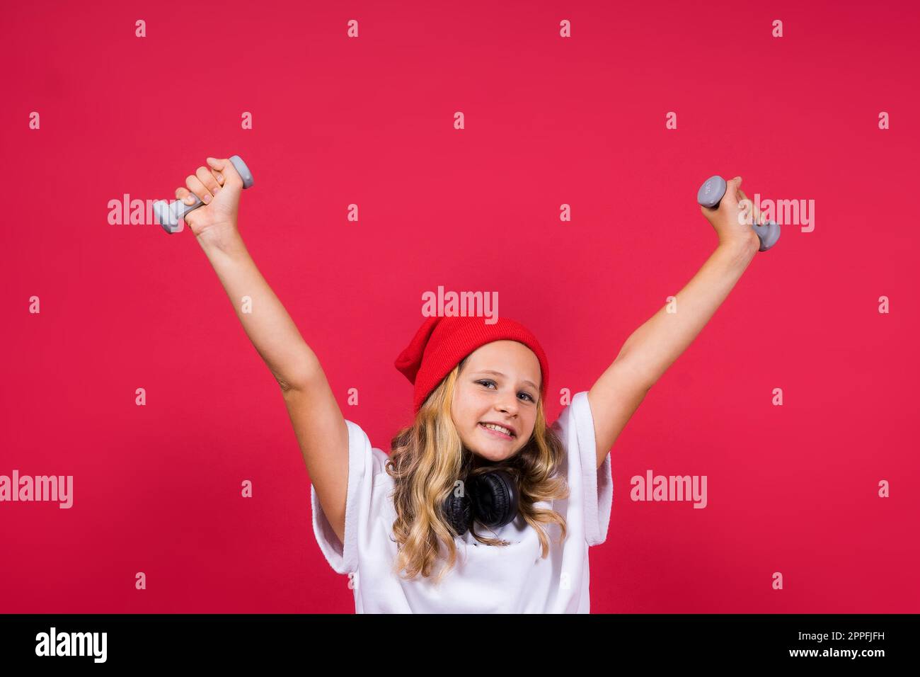 Kid girl doing fitness exercises with dumbbells on red background Stock ...