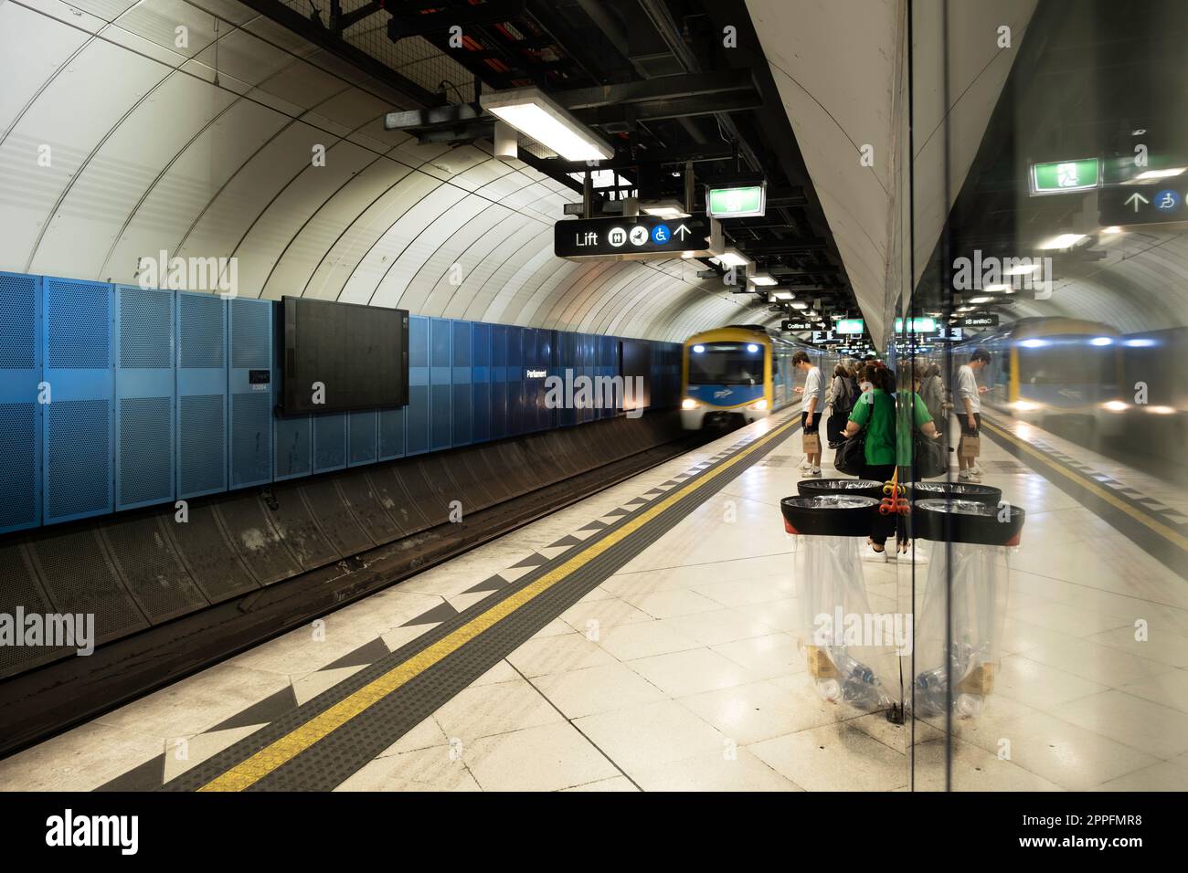 Metro train arrives at an underground platform, mirrored in the glass ...