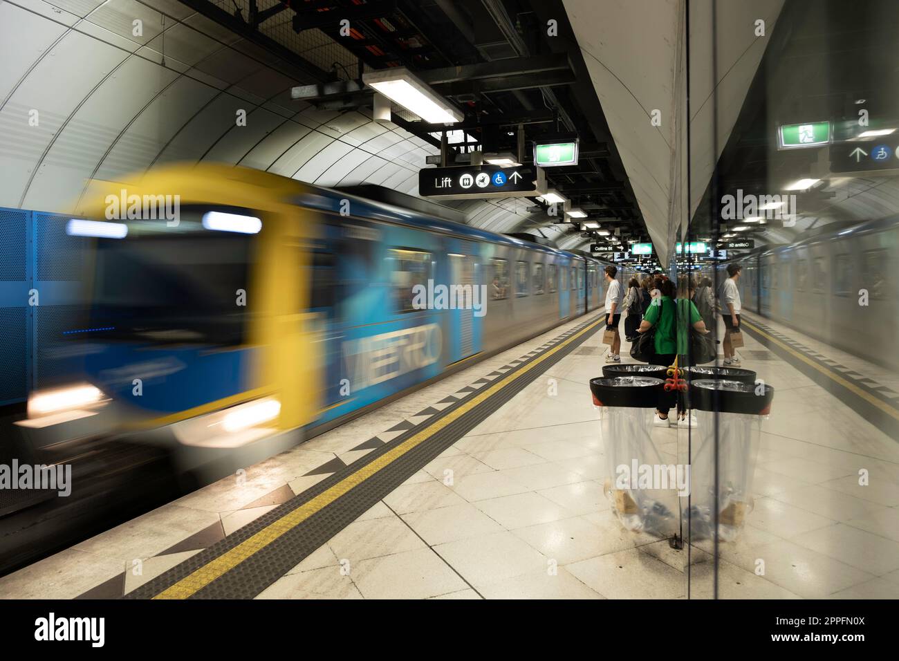 Metro train arrives at an underground platform, mirrored in the glass ...