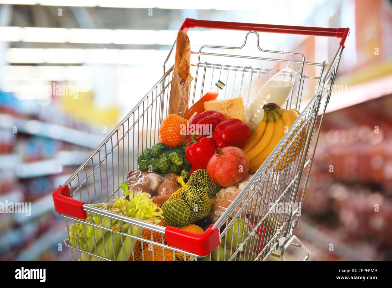Shopping cart with different groceries in supermarket Stock Photo - Alamy