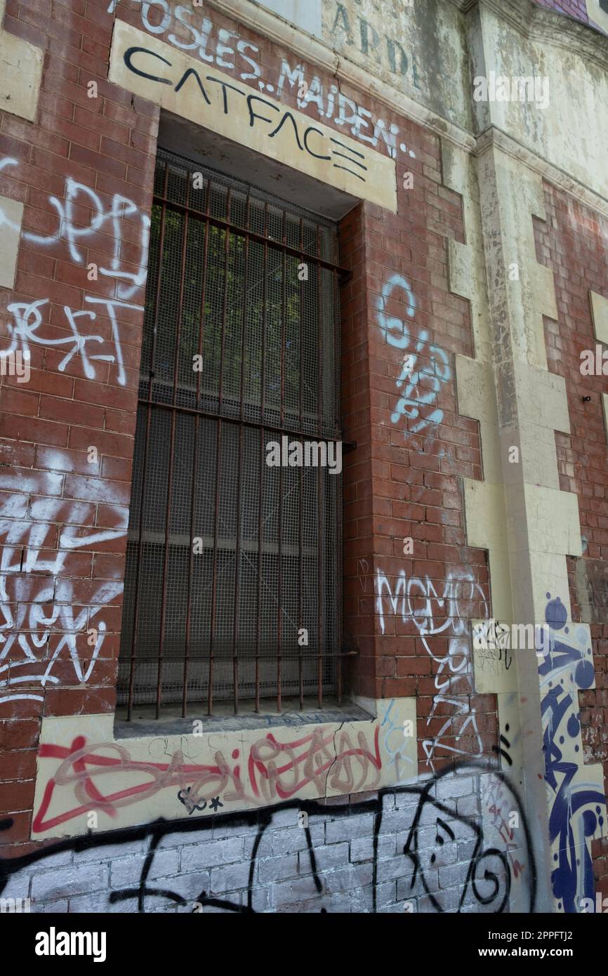 Graffiti on a brick wall around an old barred window created by unknown ...