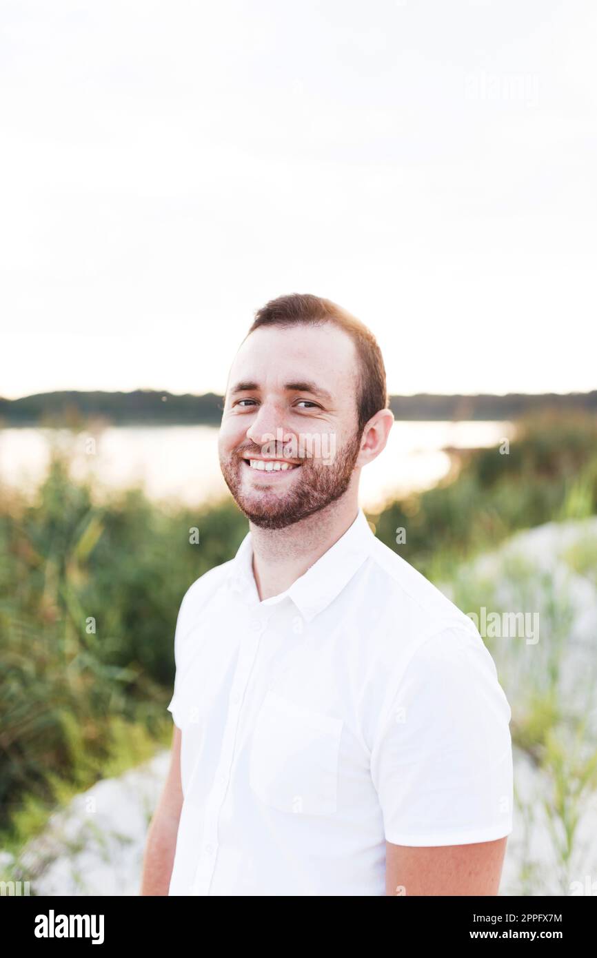 young bearded man in white shirt on beach in summer Stock Photo - Alamy