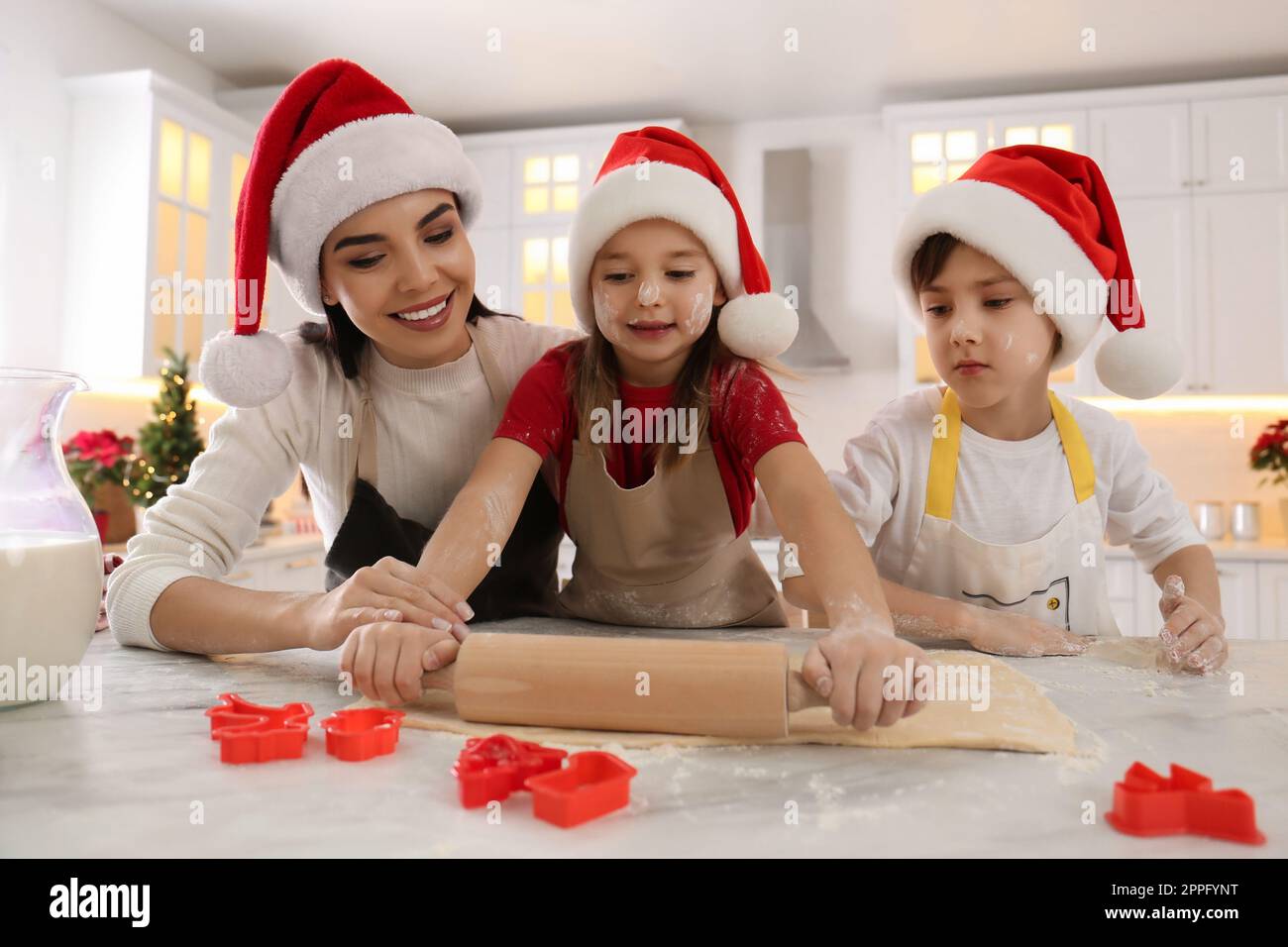 Mother and her cute little children making Christmas cookies in kitchen ...