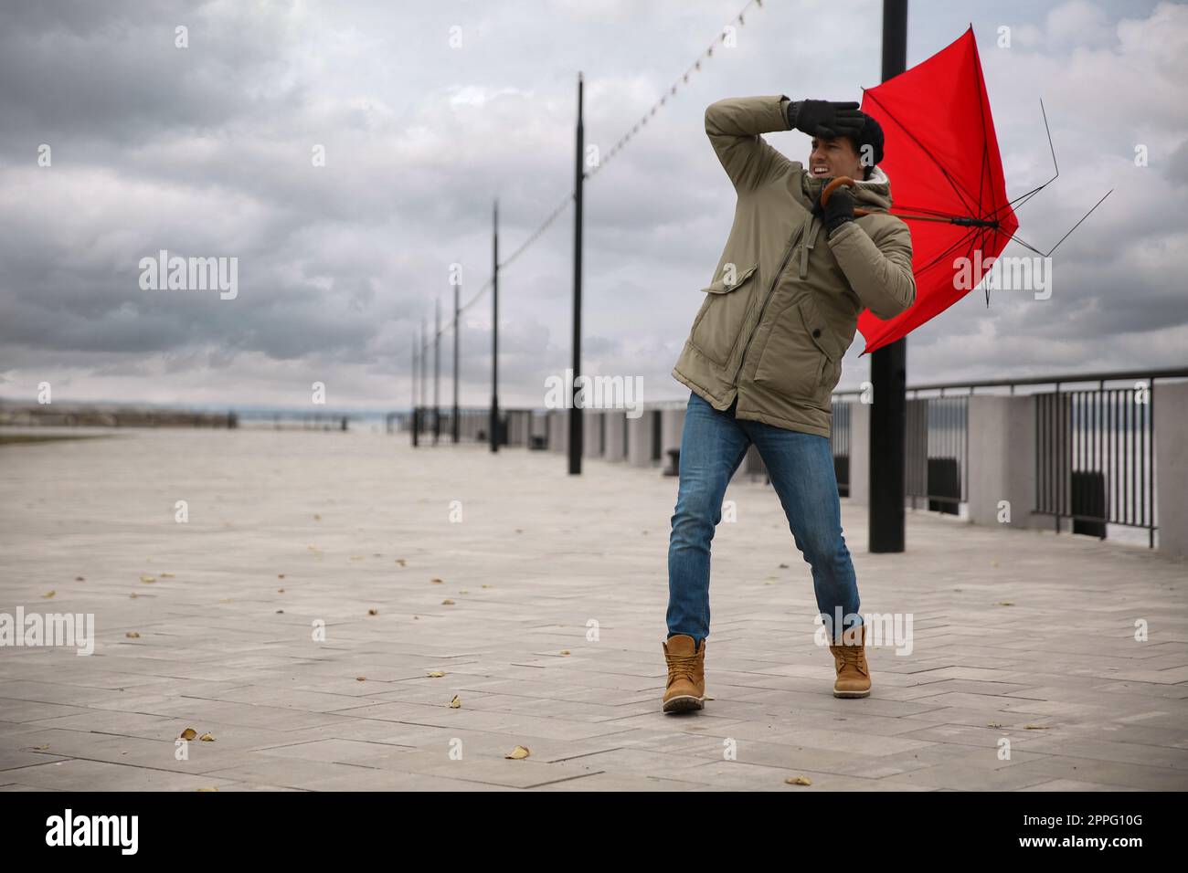 Man with red umbrella caught in gust of wind outdoors Stock Photo - Alamy