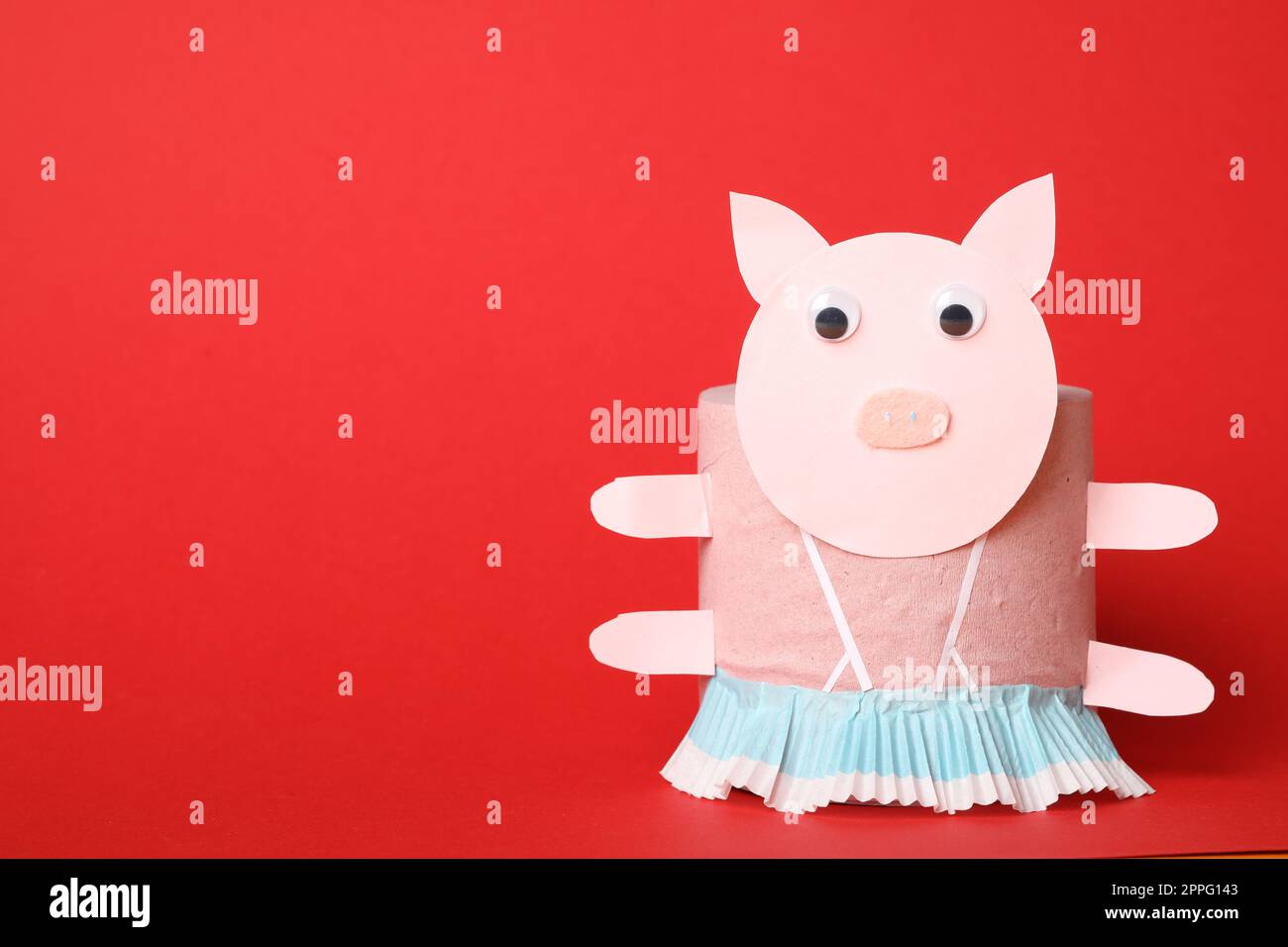 Toy pig made of toilet paper roll on red background. Space for text ...