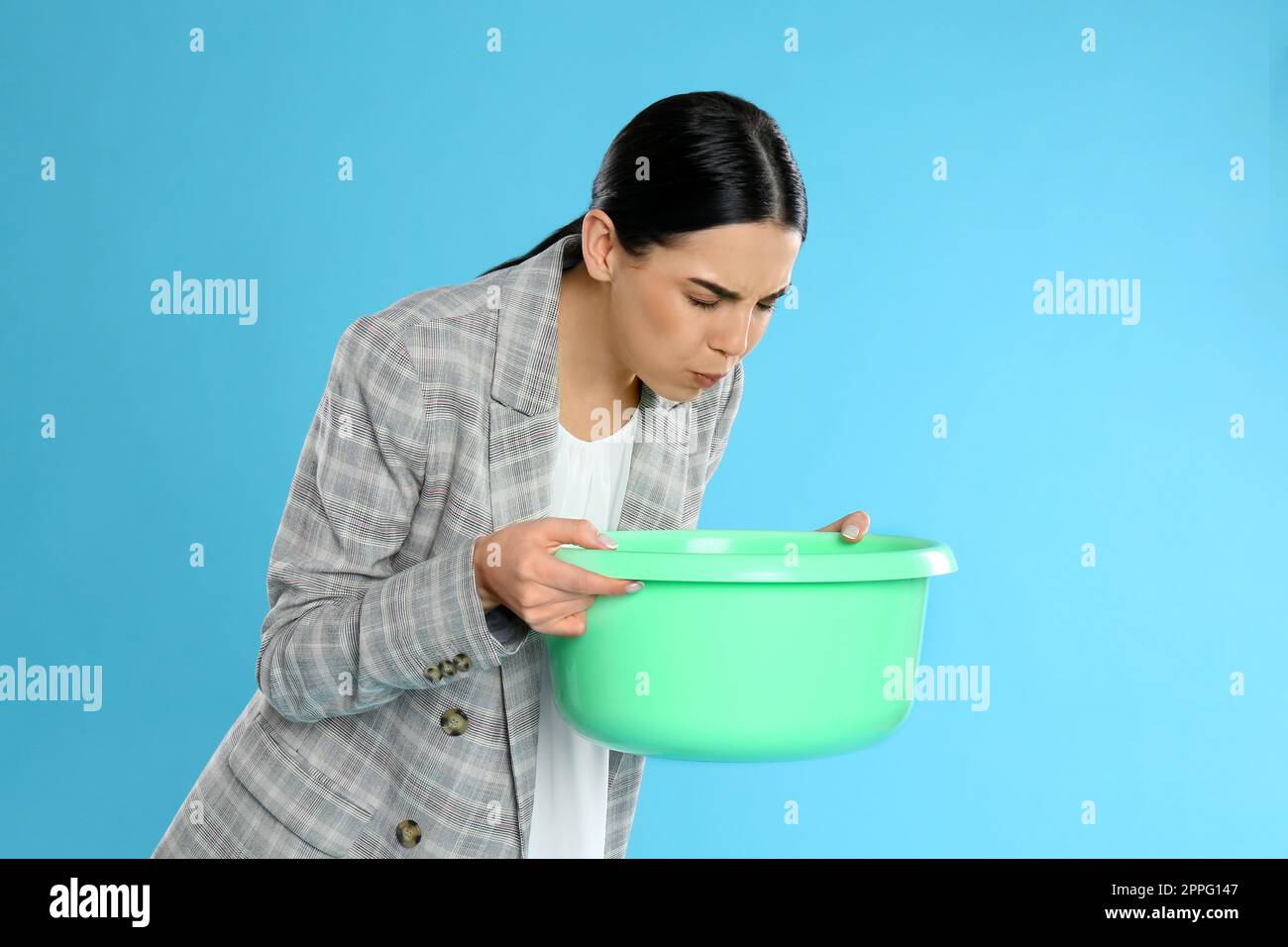 Woman with basin suffering from nausea on light blue background. Food ...